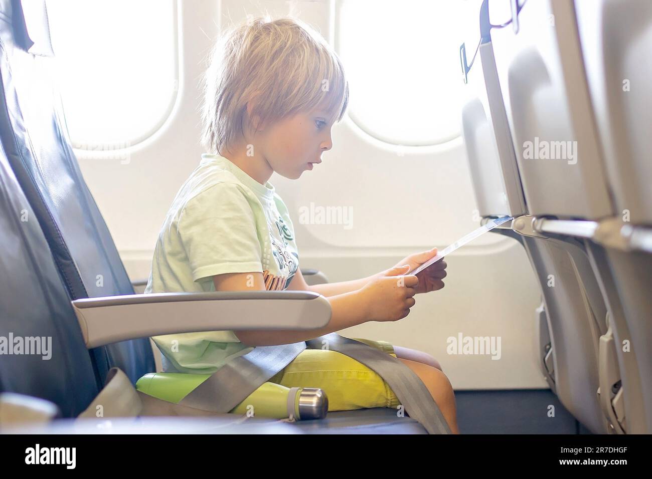 Cute preschool child, flying on a long distant flight, eating burger in ...