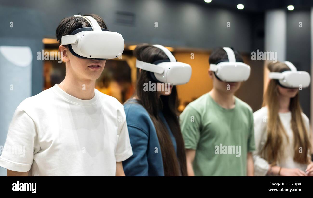 Four teenagers staying in line wearing VR equipment Stock Photo - Alamy
