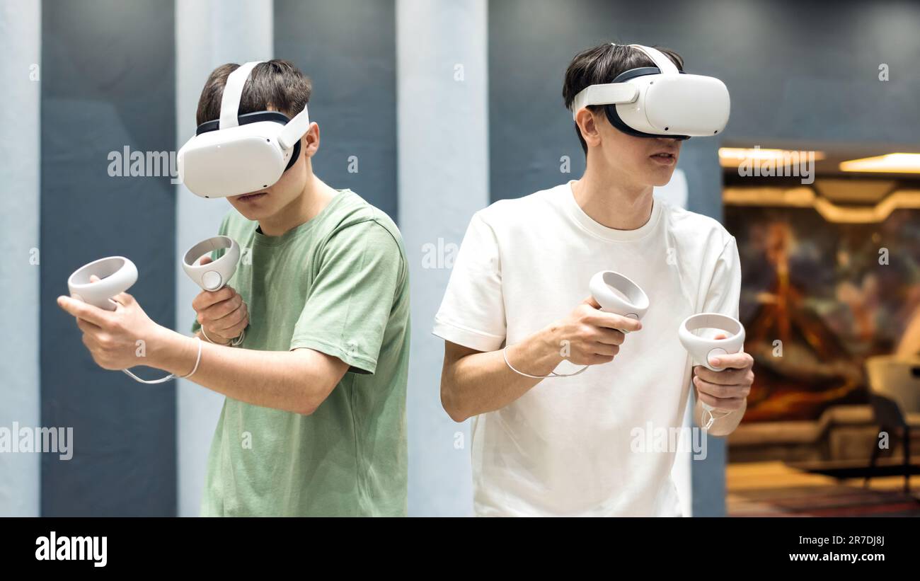 A team of friends playing with VR equipment. Two boys wearing VR ...