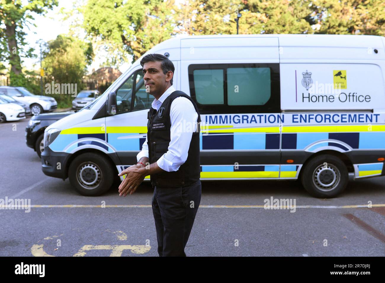 Britain's Prime Minister Rishi Sunak stands alongside an immigration ...