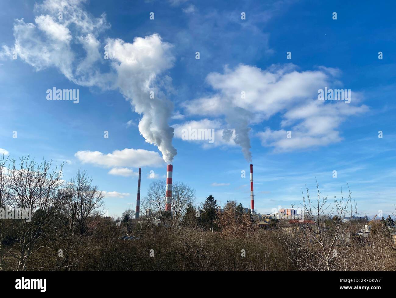An industrial factory with pipes emitting white smoke into the sky ...