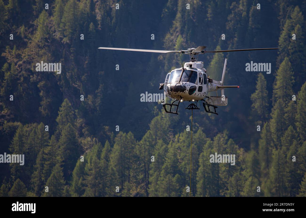 Close-up of a helicopter flying over the forest with attached ...