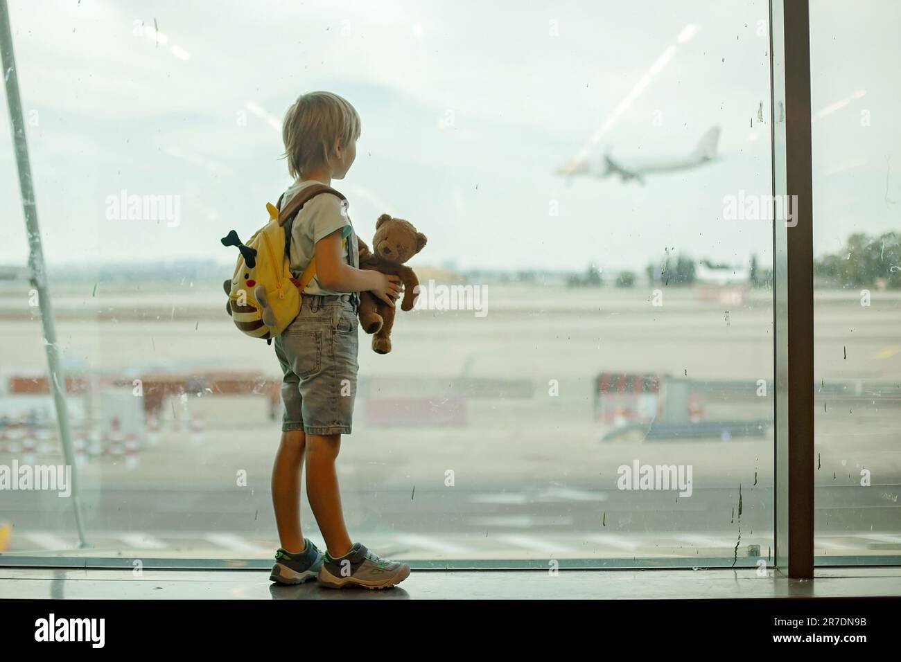 Child, watching from the window of the airport the planes, taking off ...