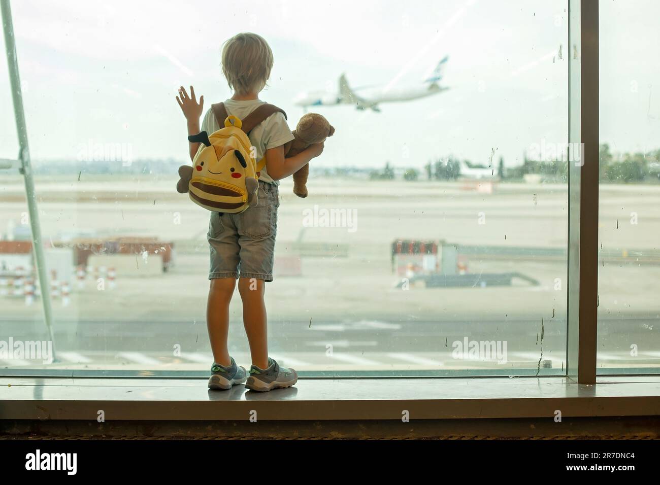 Child, watching from the window of the airport the planes, taking off ...