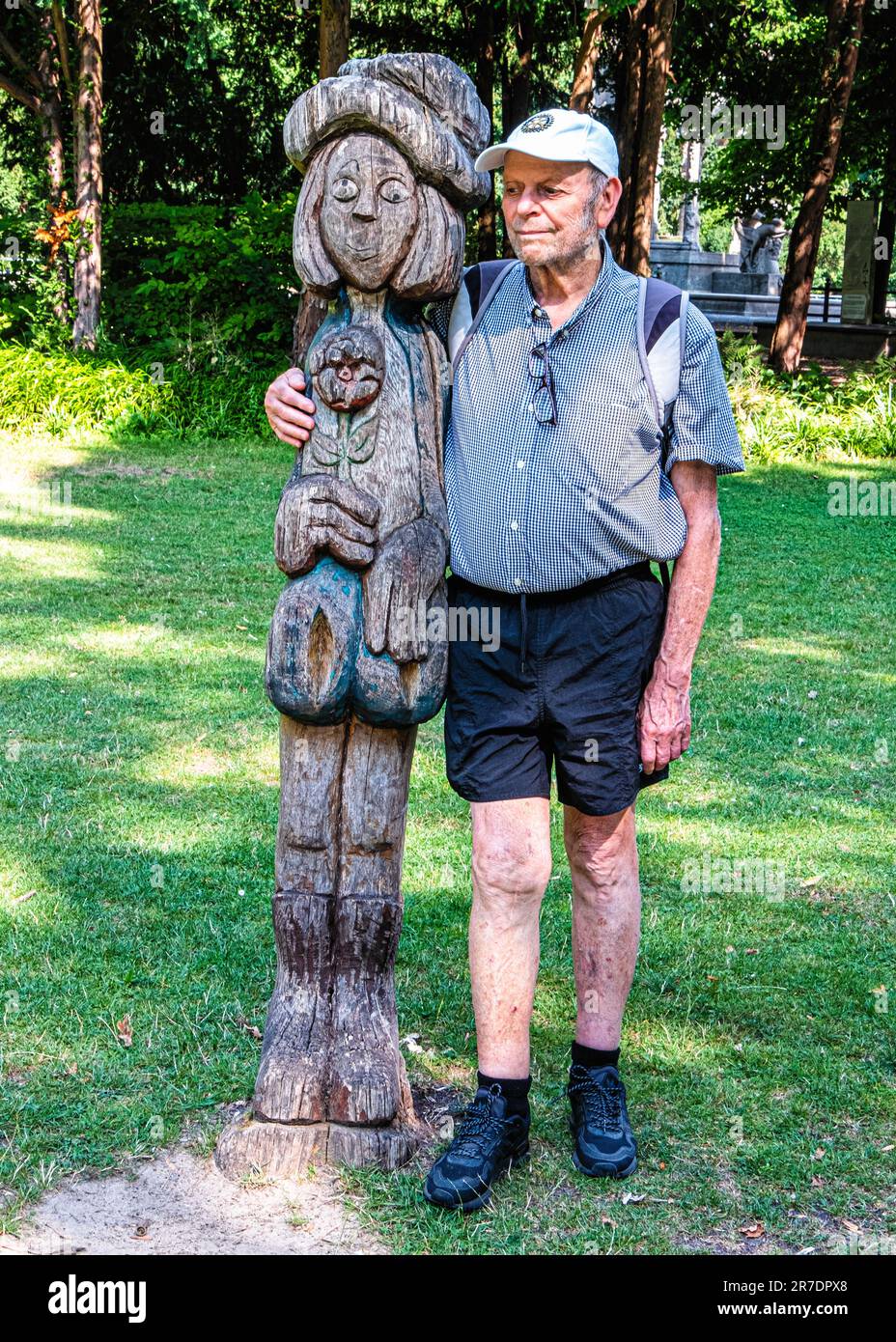 Aged statue & elderly man. Wooden sculpture depicts fairy tale figure ...