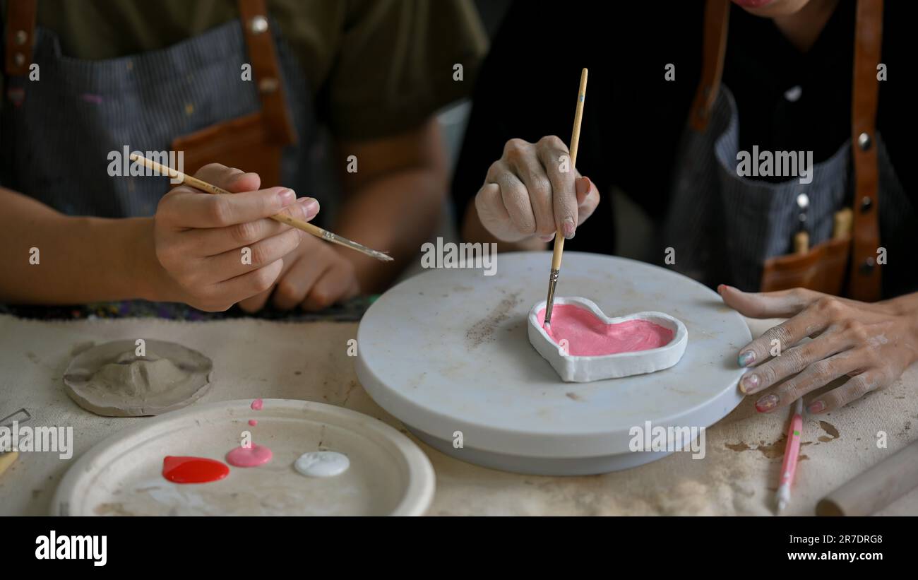 Close-up image of a man enjoys painting a ceramic heart plate in a ...