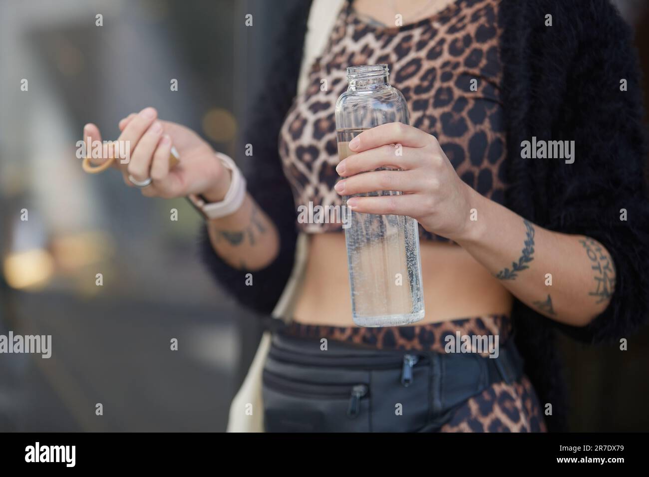 Trendy young woman in leopard clothes drinking water from a reusable ...