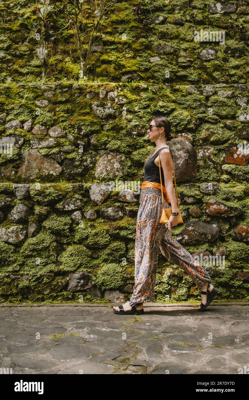 Walking young stylish girl on temple wall background. Puru Gunung Kawi ...