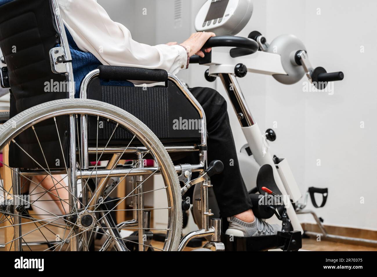 An unrecognizable elderly woman does pedal exercises from wheel chair ...