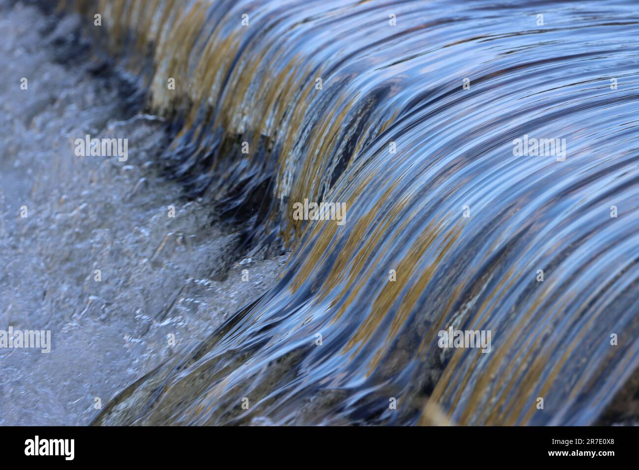 A peaceful stream of water cascading over a concrete ledge, creating a ...