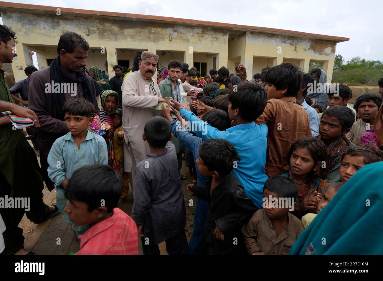 Volunteers distribute food items among children at a camp set up in a ...