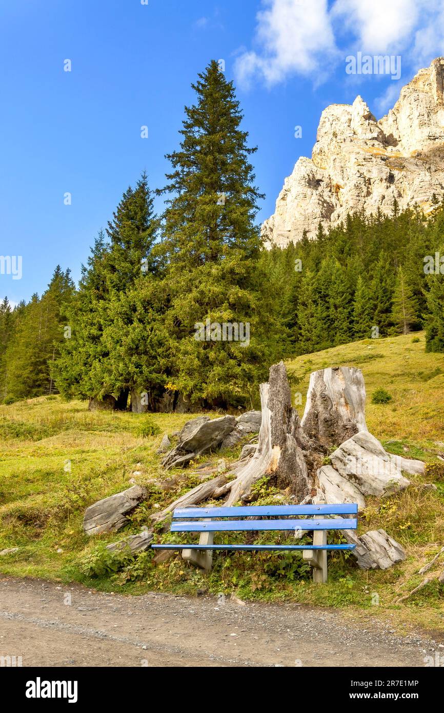 Blue bench on the pathway to Oeschinnensee lake and Swiss Alps panorama ...