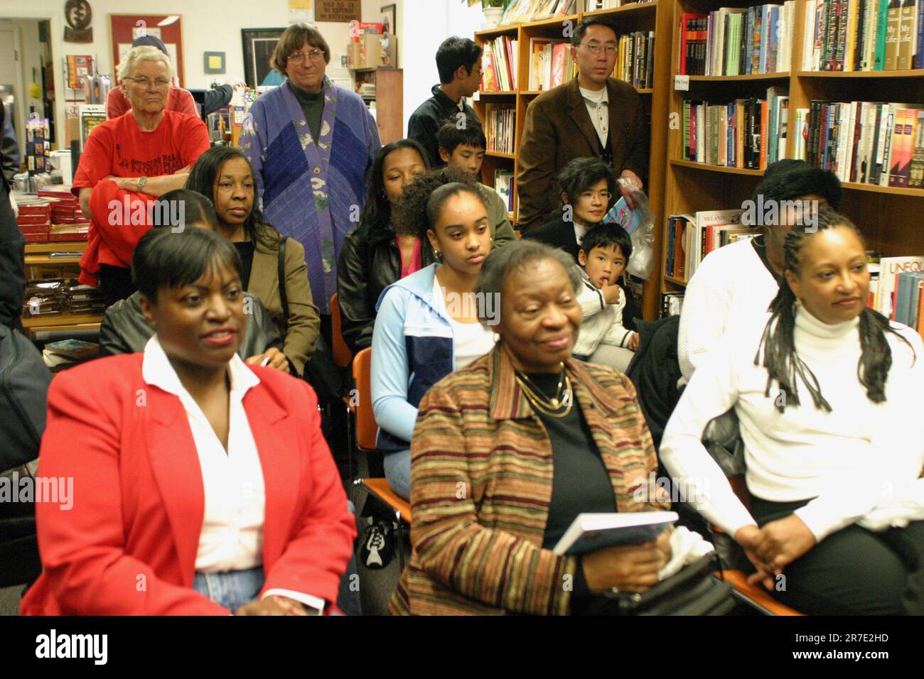A diverse group of people in a library, surrounded by bookshelves ...