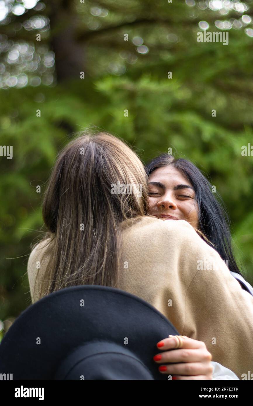 Two female friends embracing in a warm embrace while basking in the sun ...