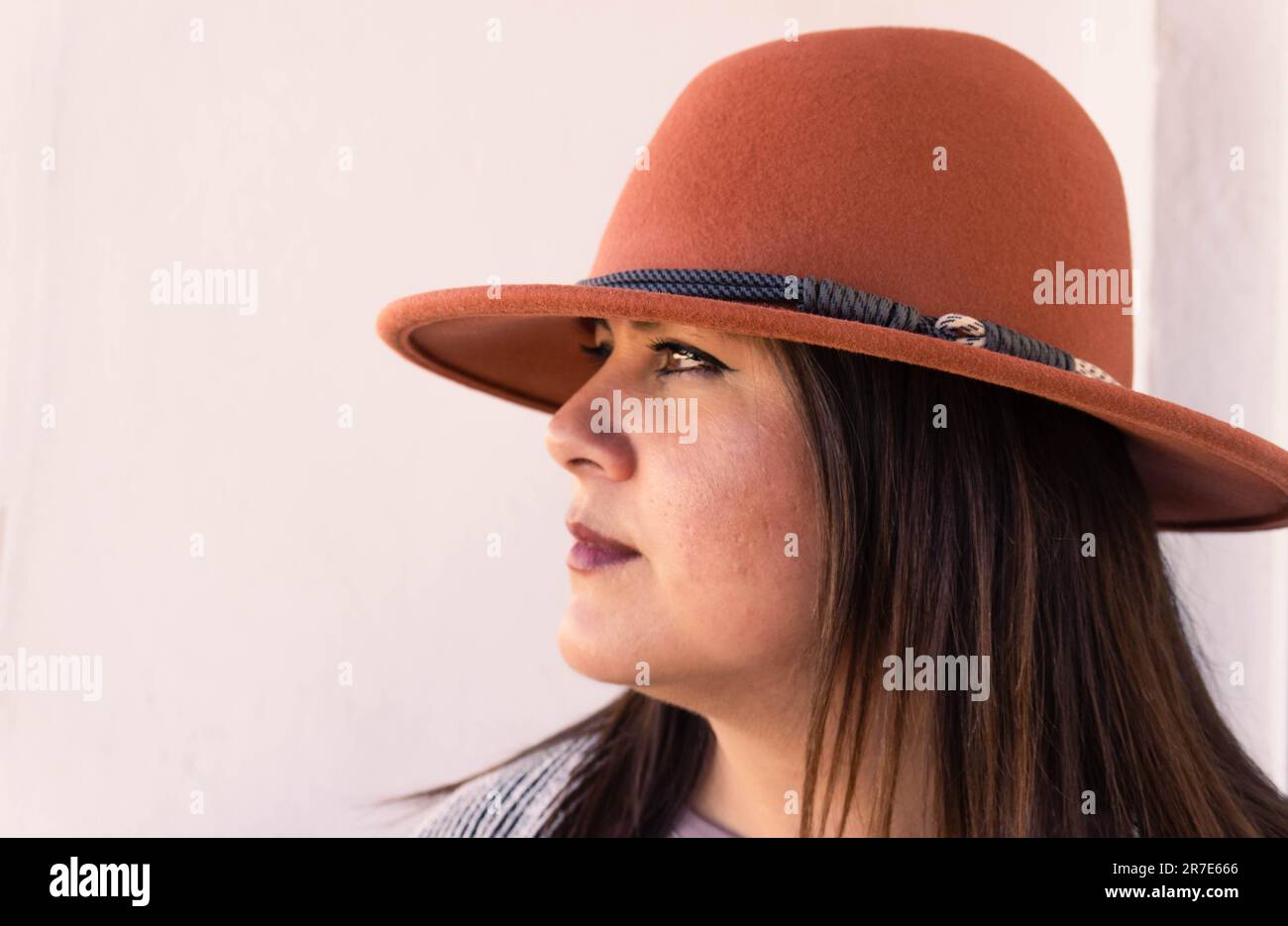 A stylish young woman wearing a brown fedora hat, looking off to the ...