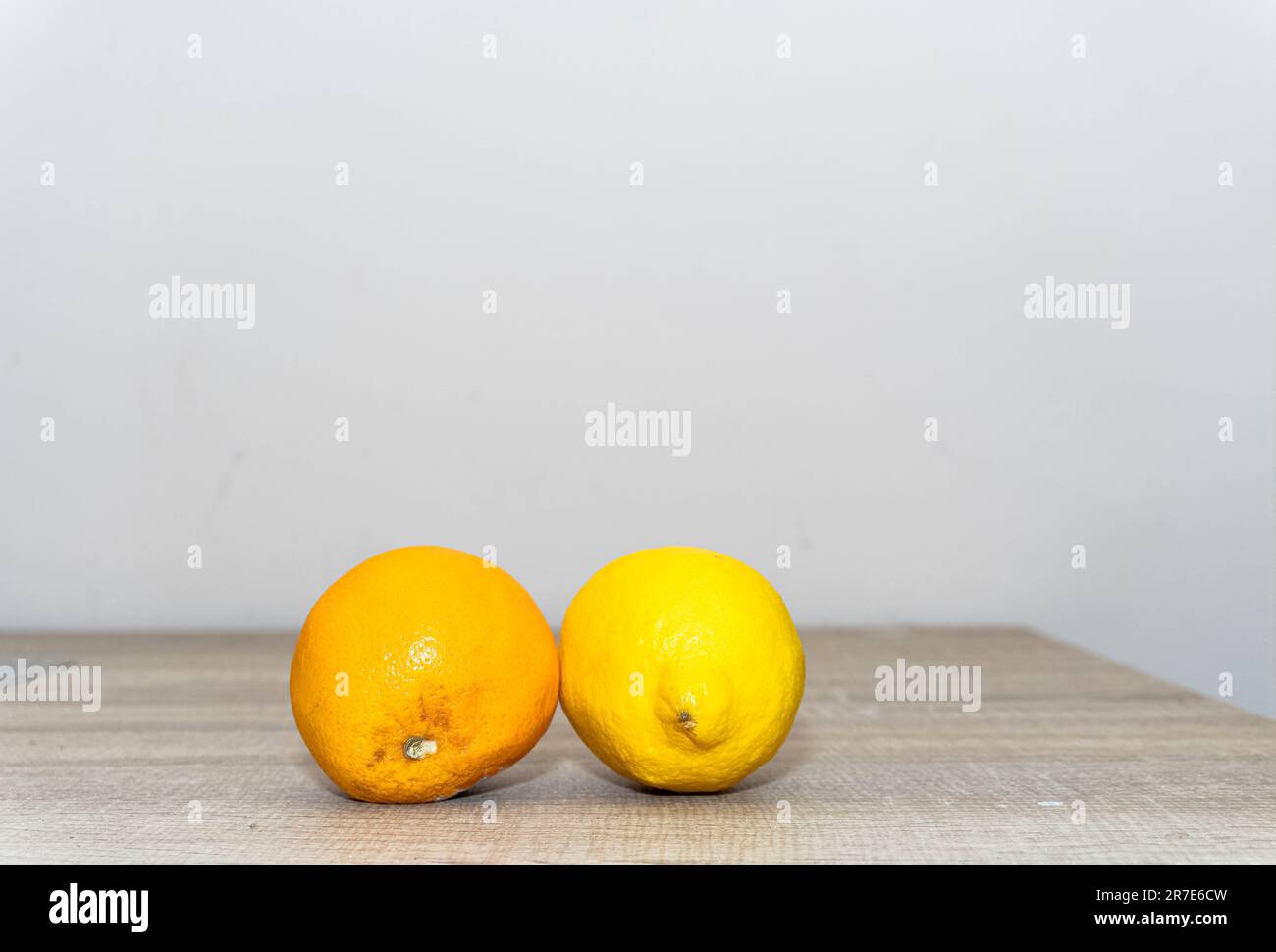 Two ripe yellow lemons laying side-by-side on a rustic wooden table top ...