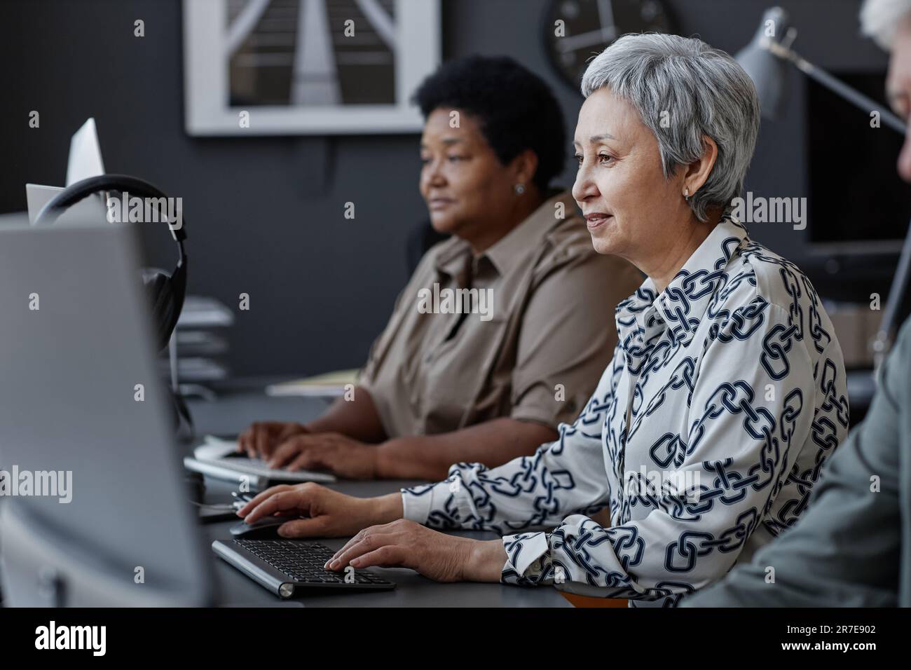 Side view portrait of Asian senior woman using computer and smiling in ...