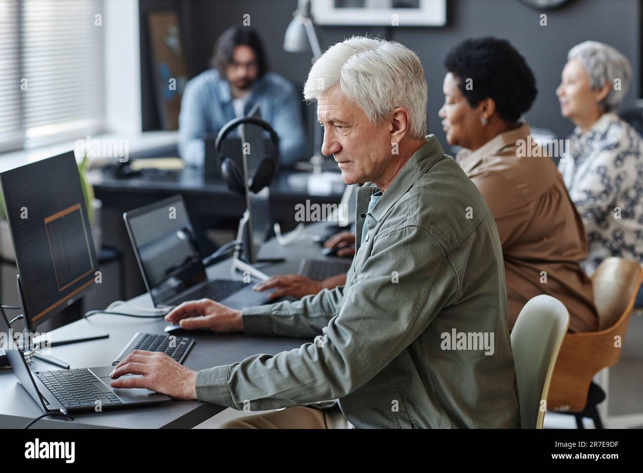 Side view portrait of white haired man using computer in programming ...