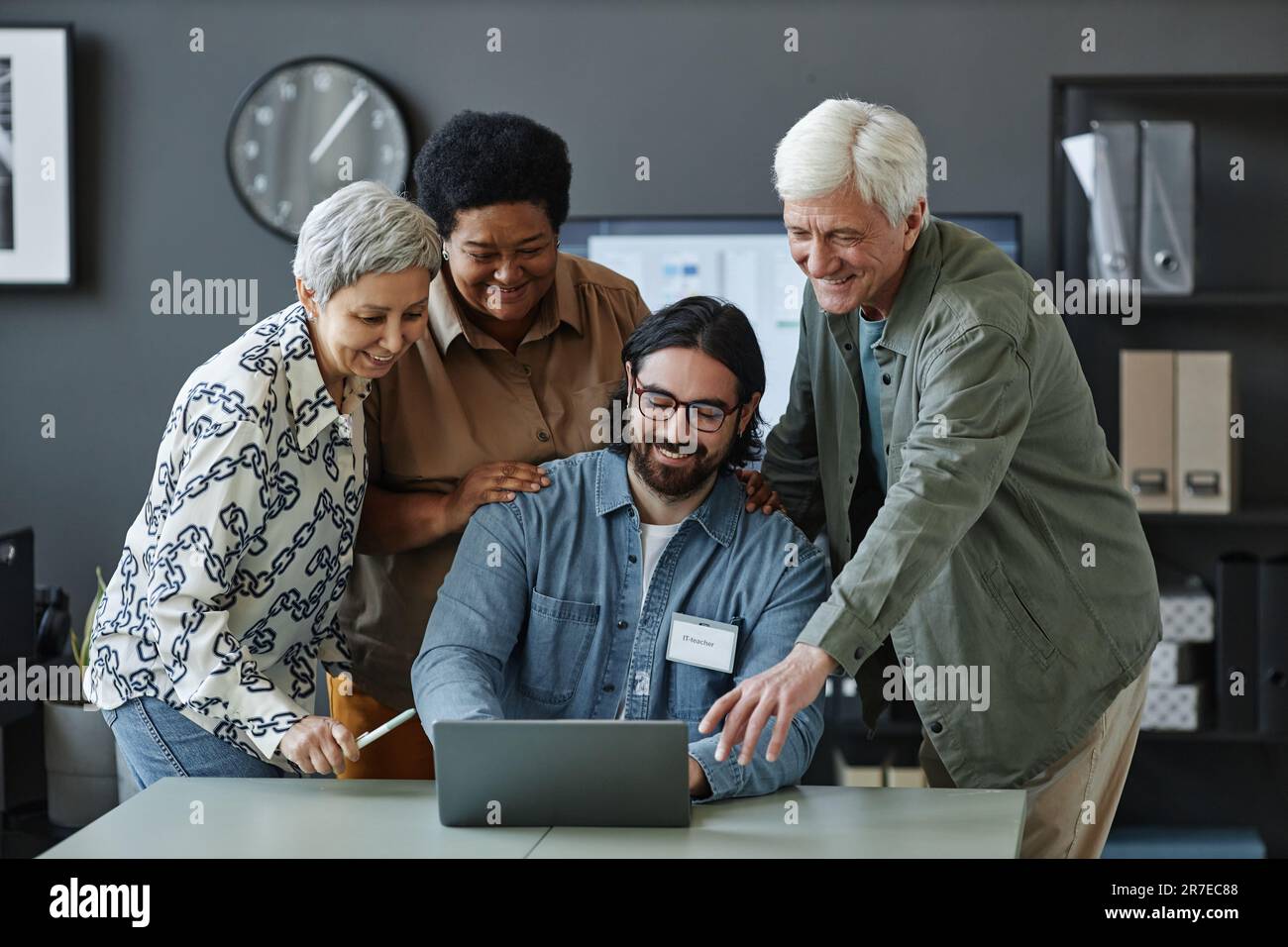 Diverse group of smiling senior people using laptop with man explaining ...