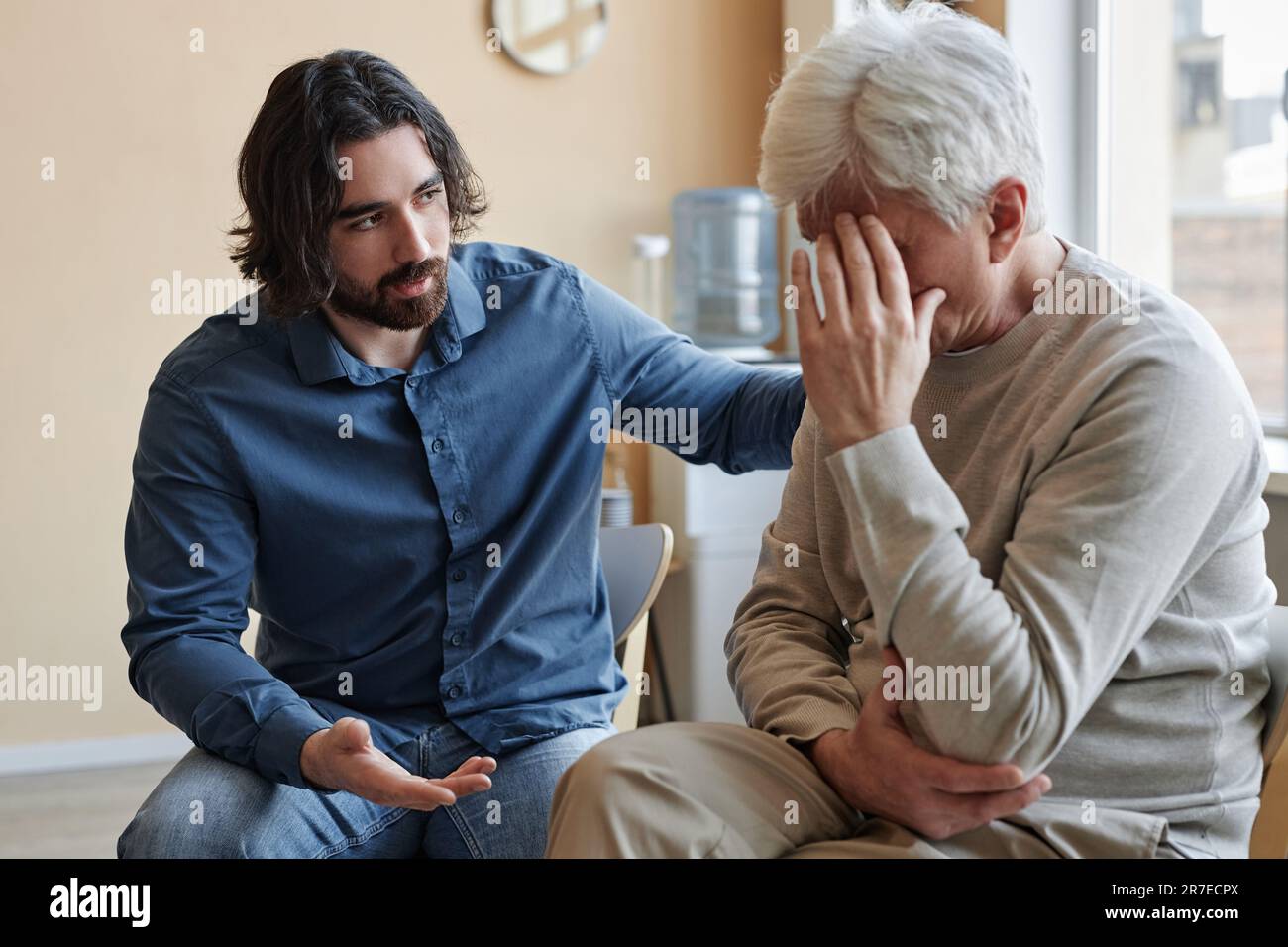 Portrait of male psychologist comforting senior man crying in mental ...
