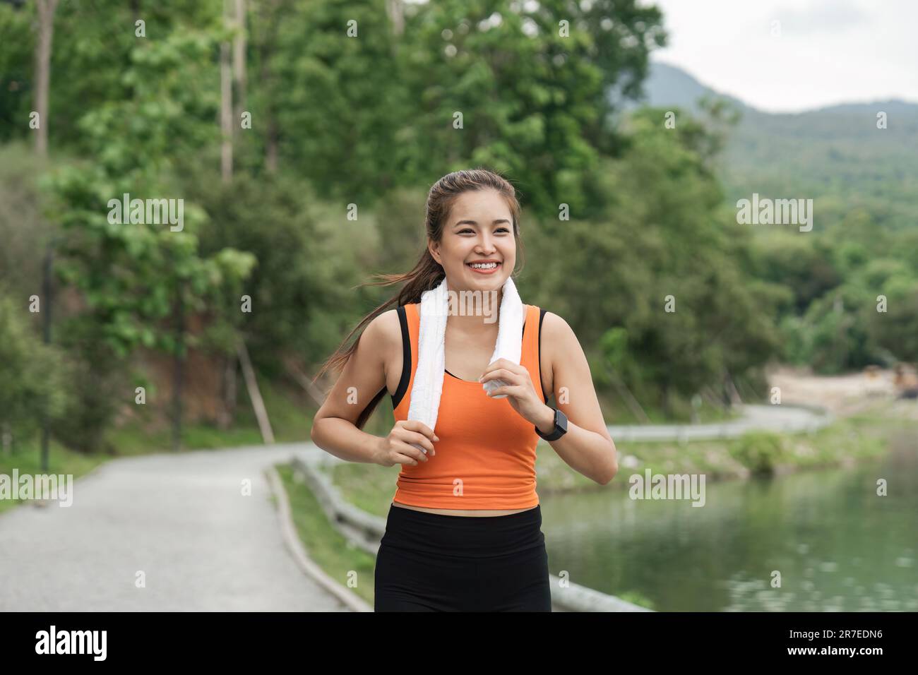 Happy woman wearing sportswear jogging in the park. Young beautiful ...