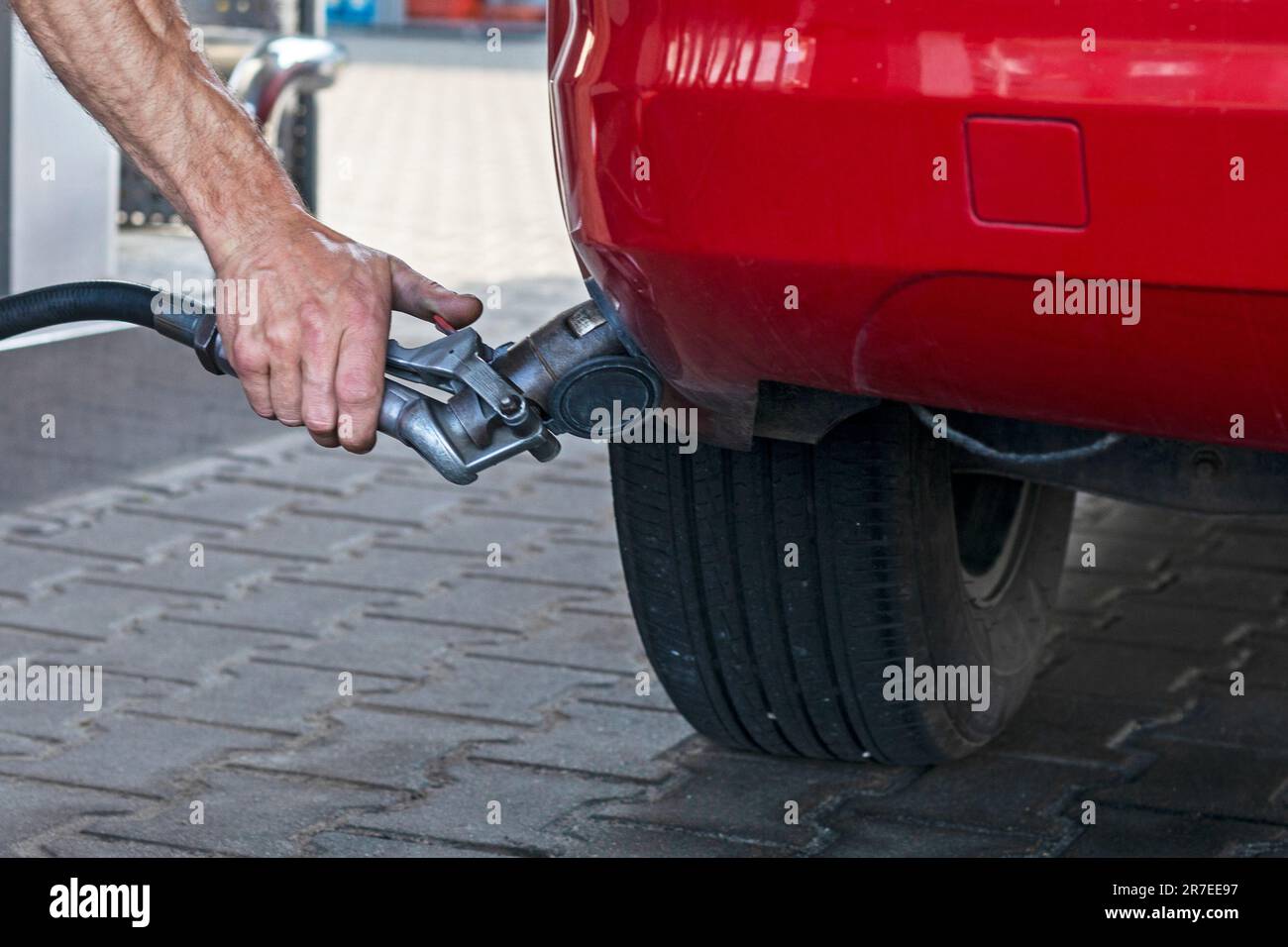 tanker filling a left side gas filling gun on a gas powered car at a ...