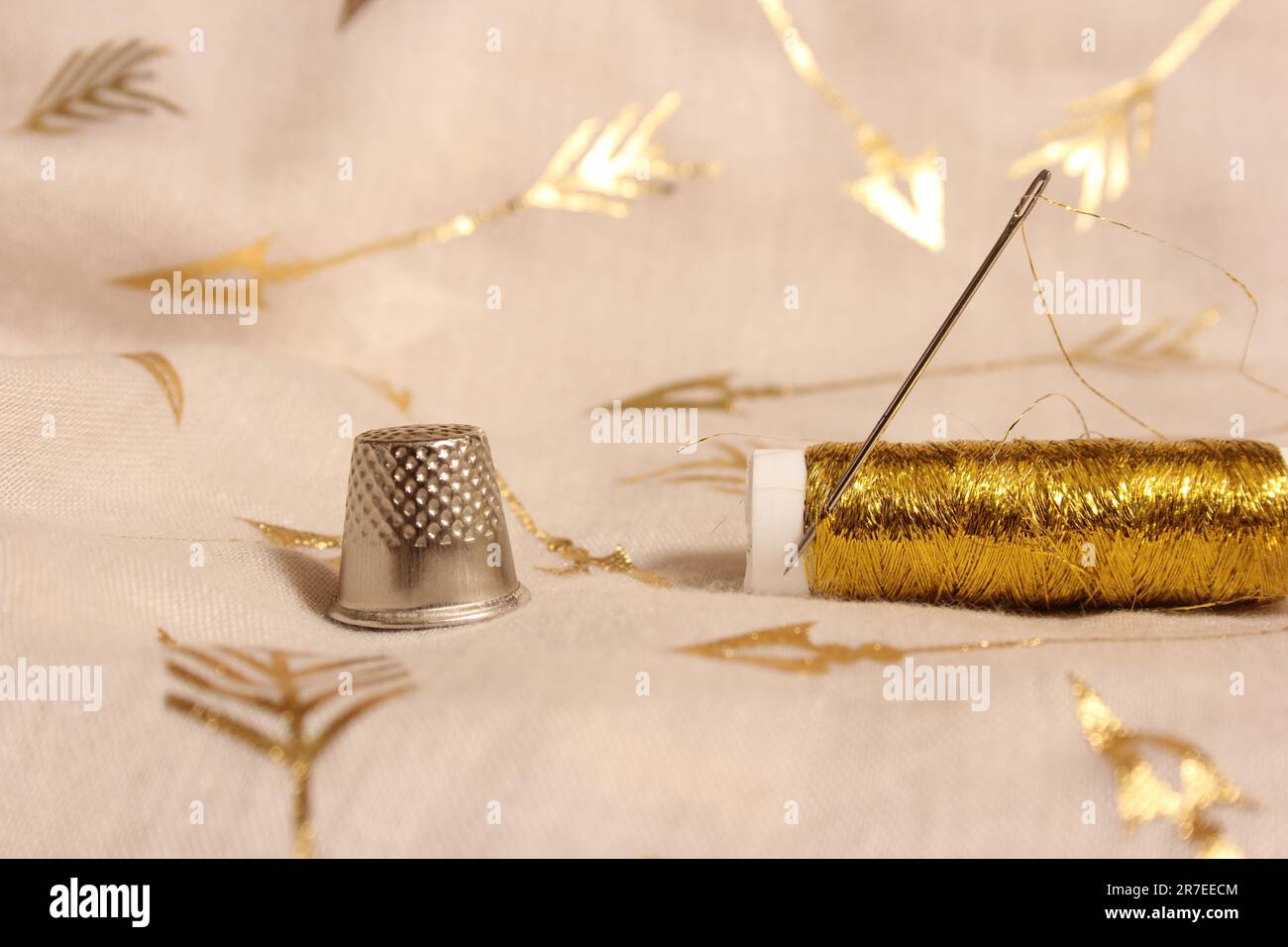Spool of Gold Thread With Thimble on Metallic Chiffon Fabric Stock ...