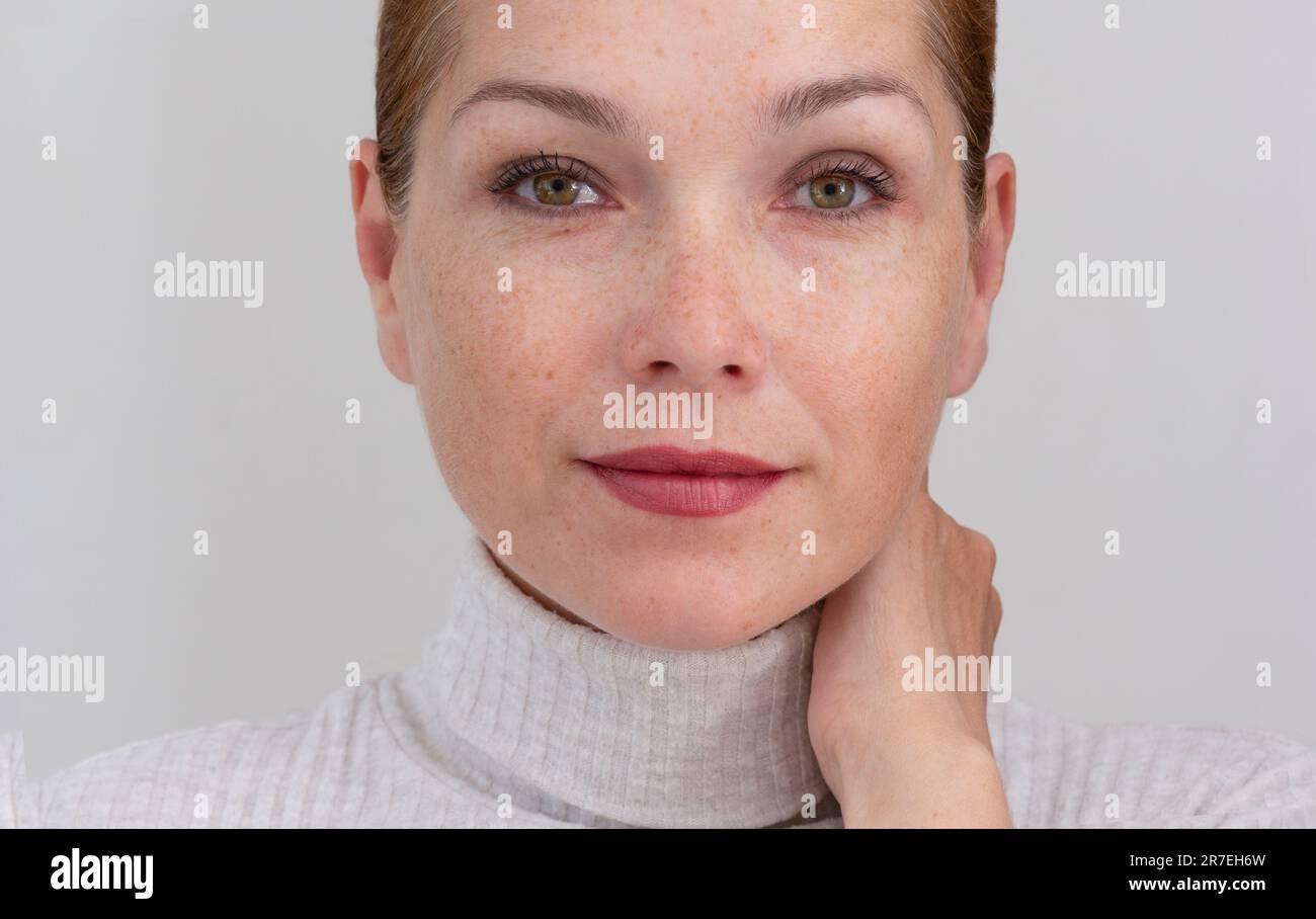 Portrait of cropped caucasian middle aged woman face with freckles on white background looking ...