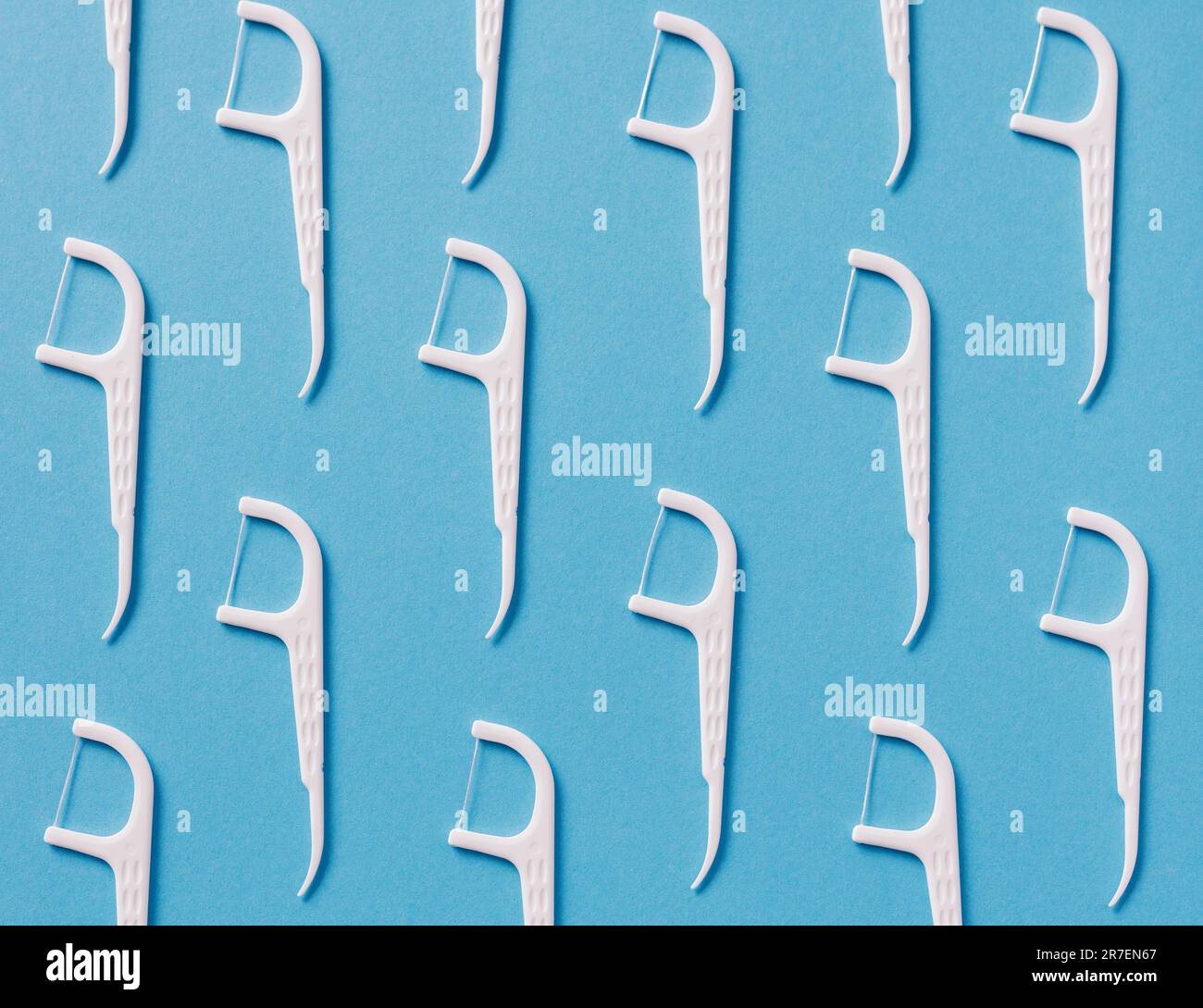 Pattern of white dental floss with a plastic toothpick on blue ...