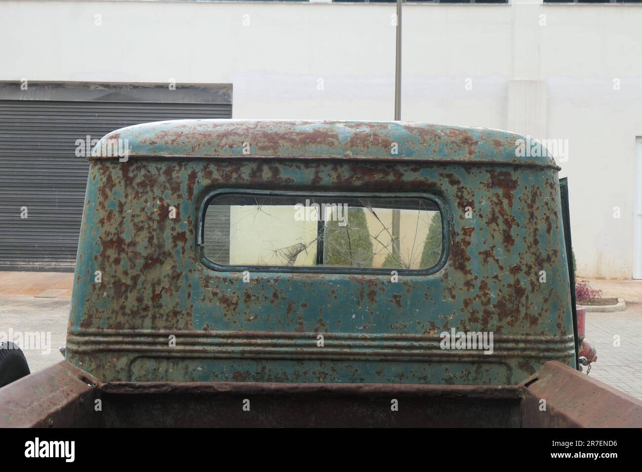 Rear view of the rusty old cabin of a light truck with a cracked window ...