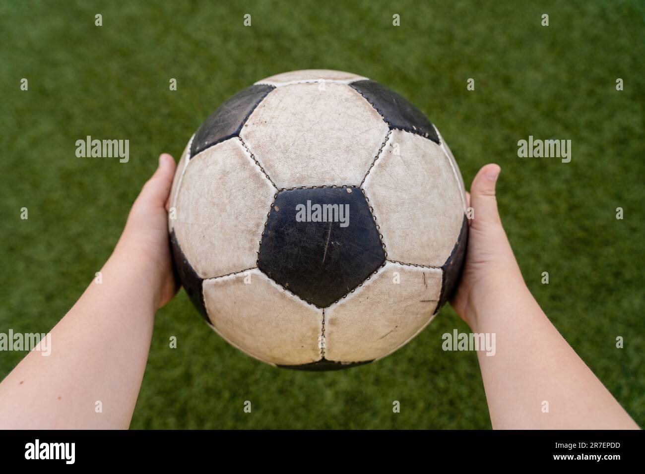 Old shabby classic football in boy's hand Stock Photo - Alamy