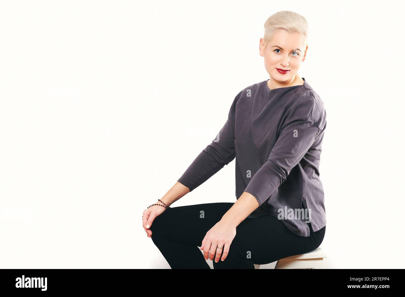 Studio portrait of mature woman posing on white background, sitting on ...