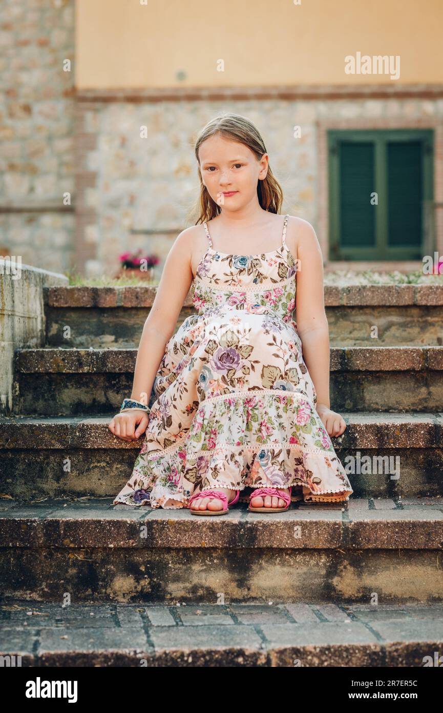 Summer portrait of cute little girl wearing long dress, sitting on ...