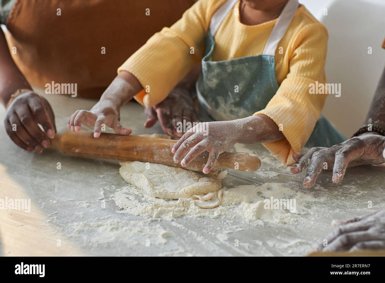 Close-up of African American little girl rolling the dough with rolling ...