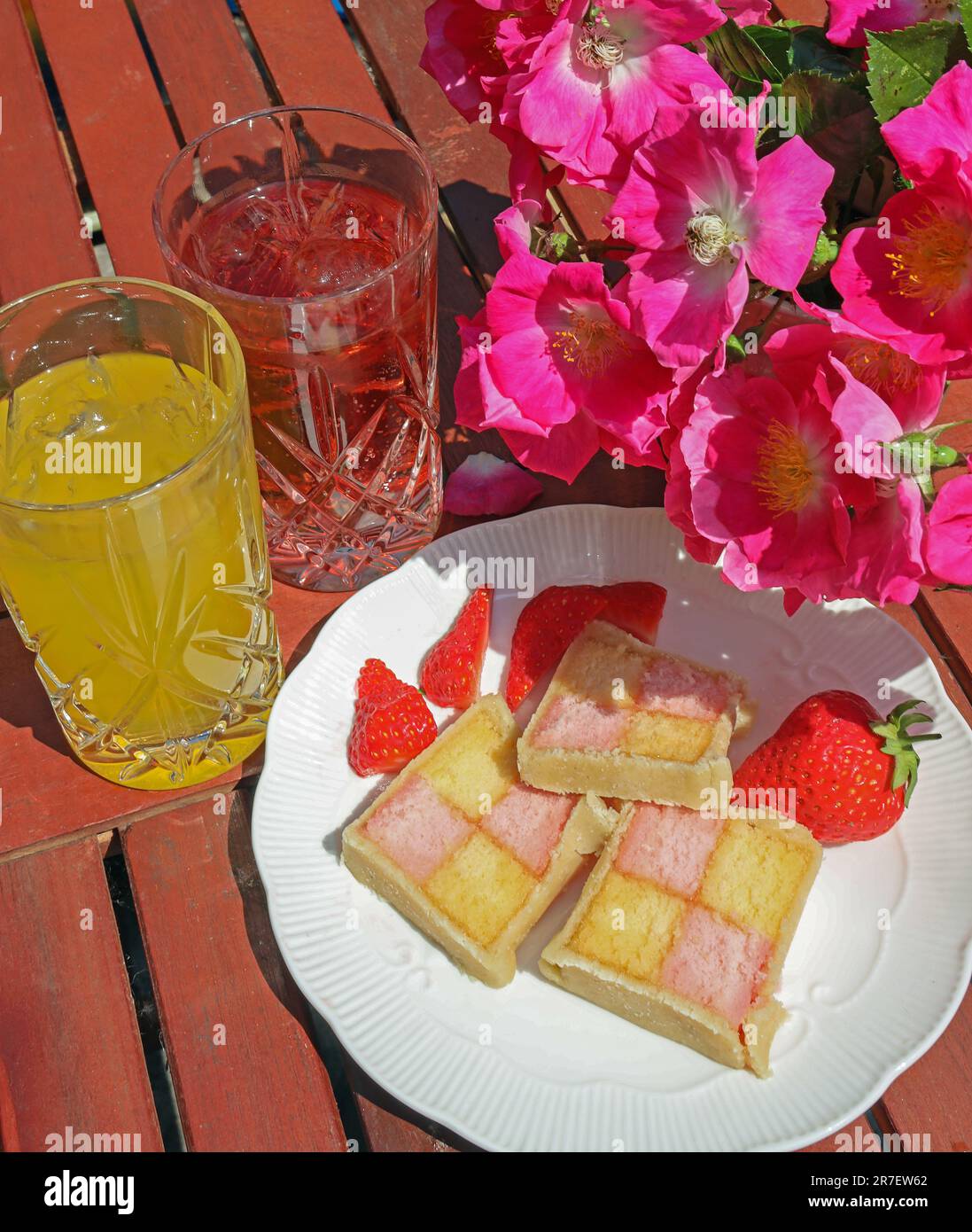 Upright image of A plate of battenberg cake slices on a slated garden ...
