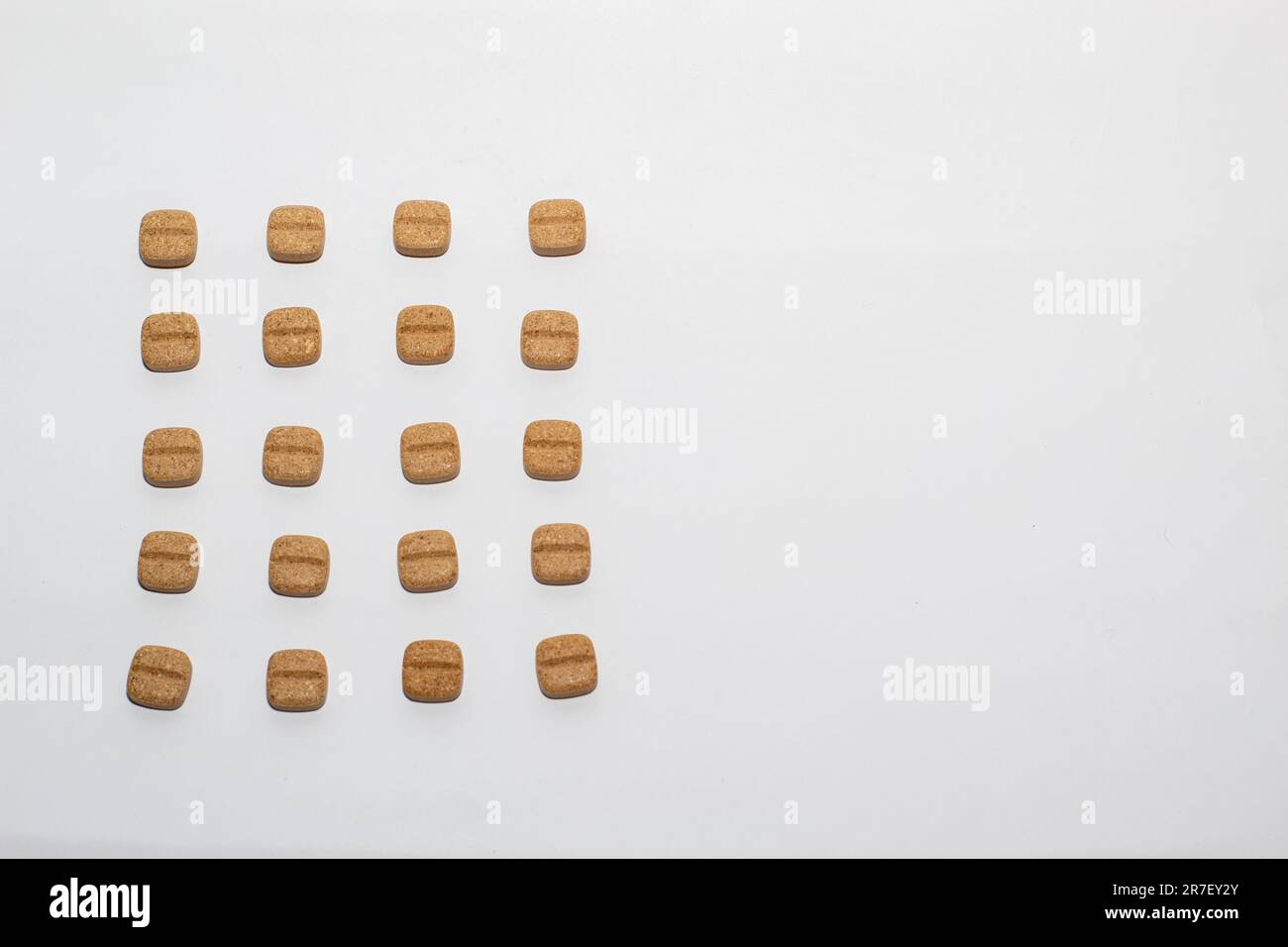 An organized grid of brown pills on a white background is depicted in ...