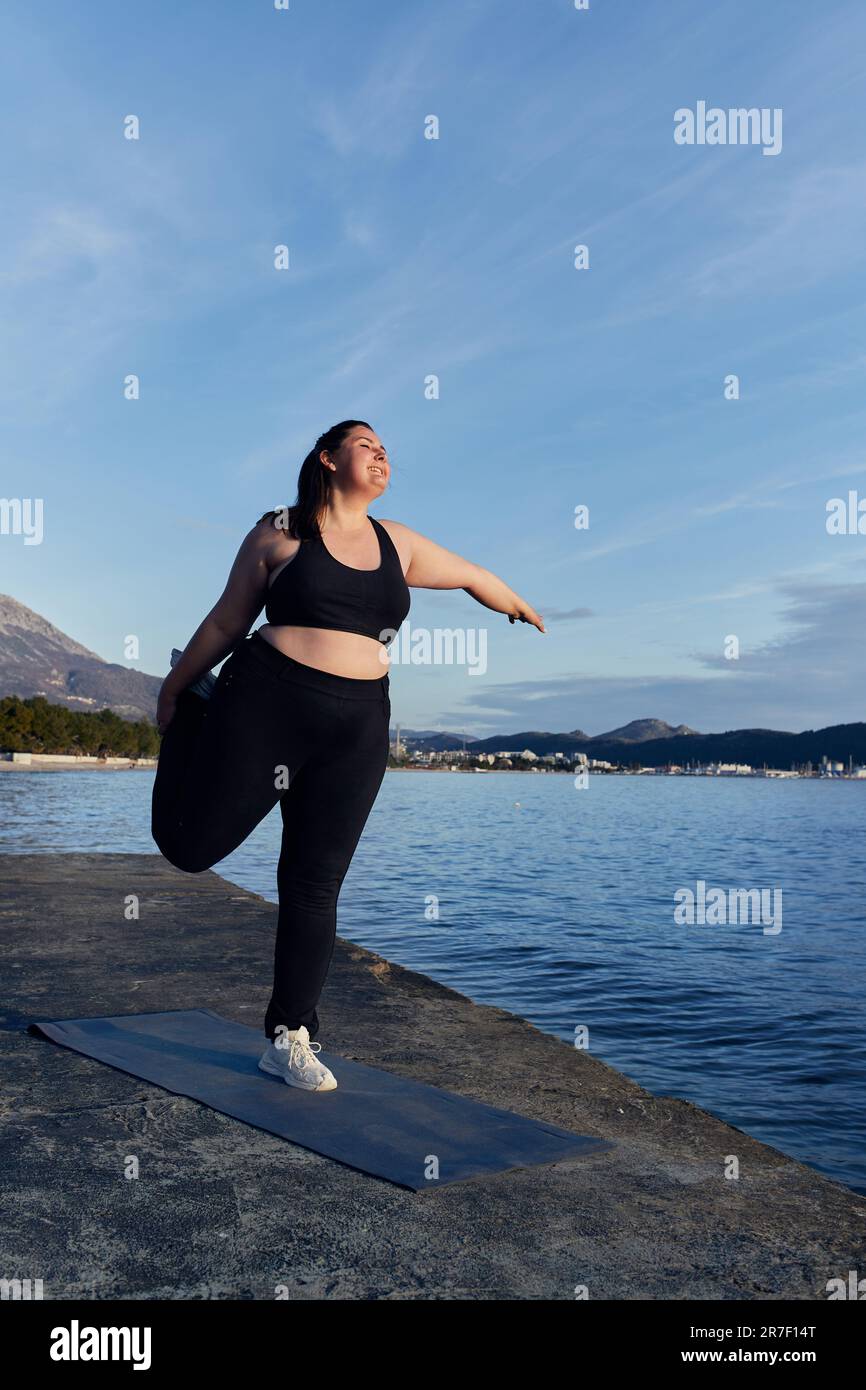 Young overweight girl does physical exercises on the seashore Stock ...