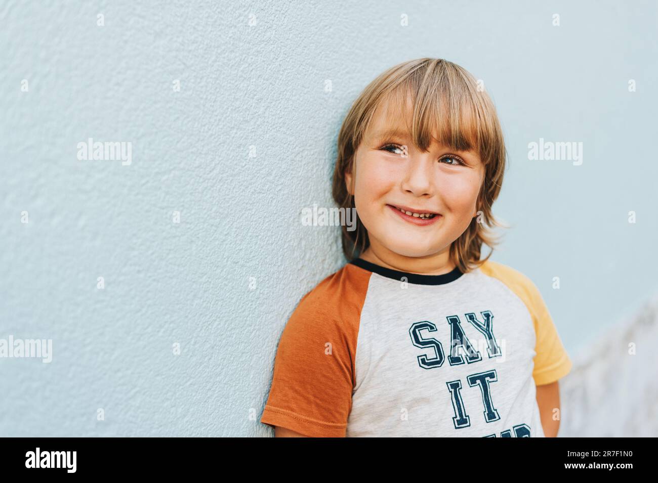 Outdoor portrait of adorable kid boy wearing t-shirt with the sign "Say ...
