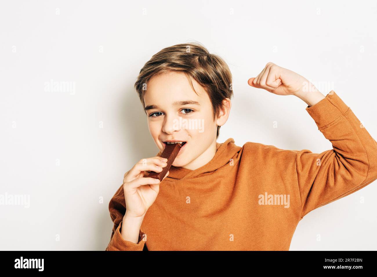 Handsome kid boy biting chocolate bar and showing arm muscle Stock ...