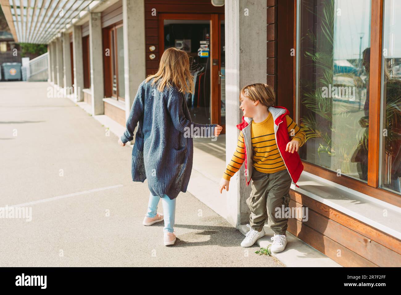 Two funny kids playing together outside, little boy and girl having fun ...