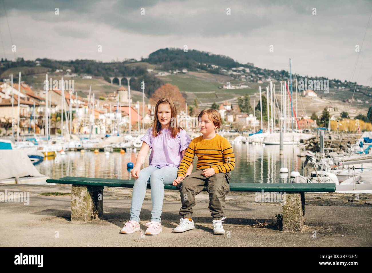 Two funny kids, little brother and sister, playing together outside by ...