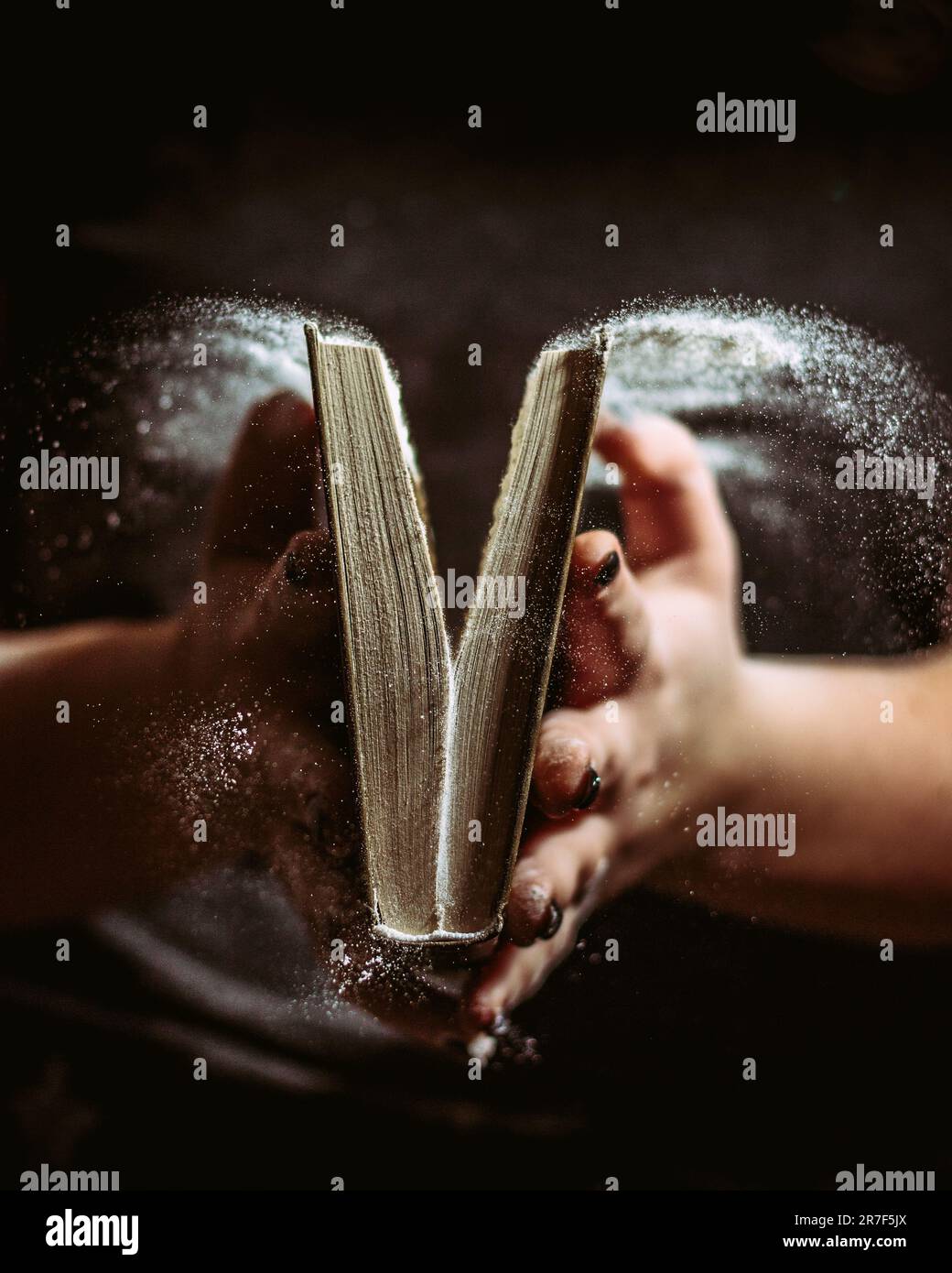 A person opening a musty hardcover book, causing a flurry of dust ...