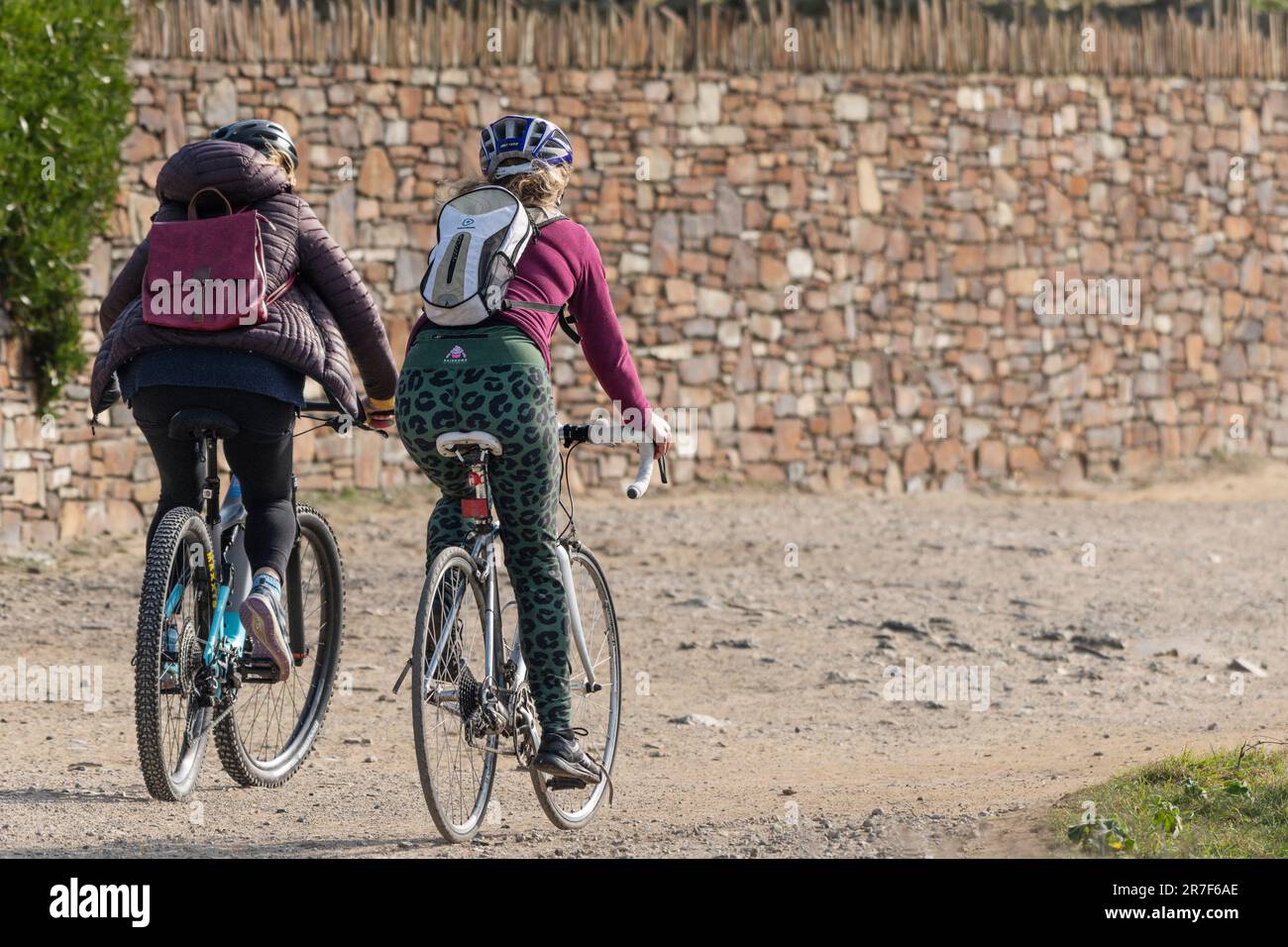 Two female cyclists cycling along the coast path in Newquay in Cornwall ...