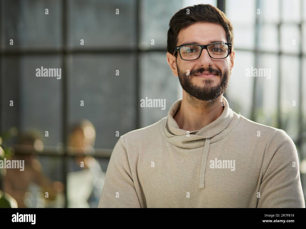 Handsome young businessman in smart casual wear keeping arms crossed ...