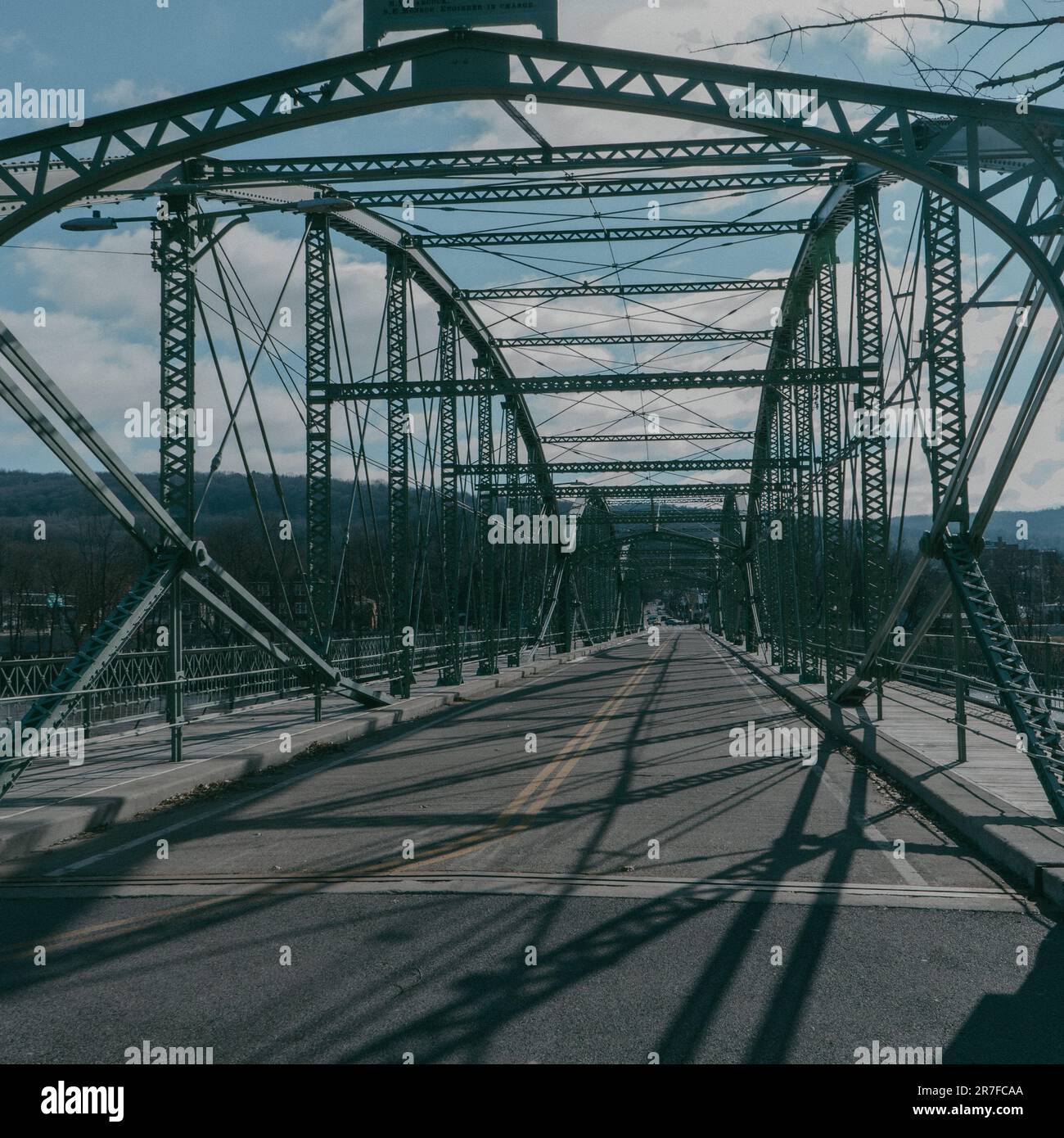 A metal bridge structure is seen traversing a wide urban road ...