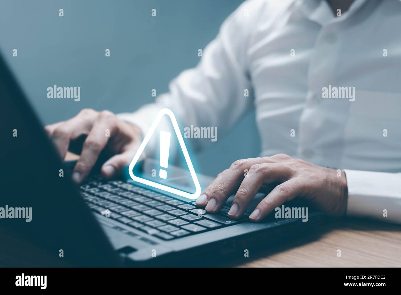 Businessman using computer laptop with triangle caution warning sing ...