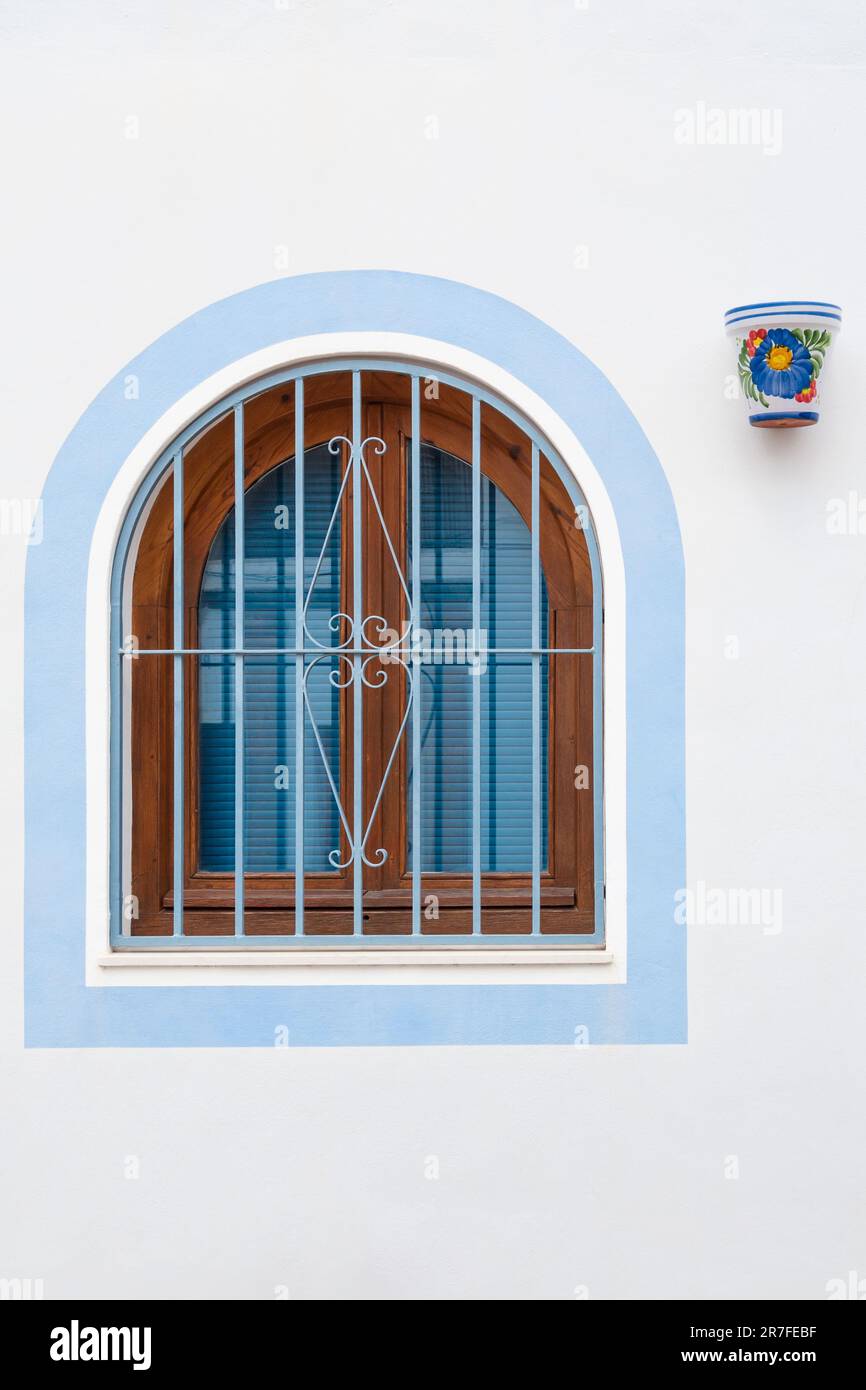 A Wooden window with bars with blue rims and a decorative plant pot on ...