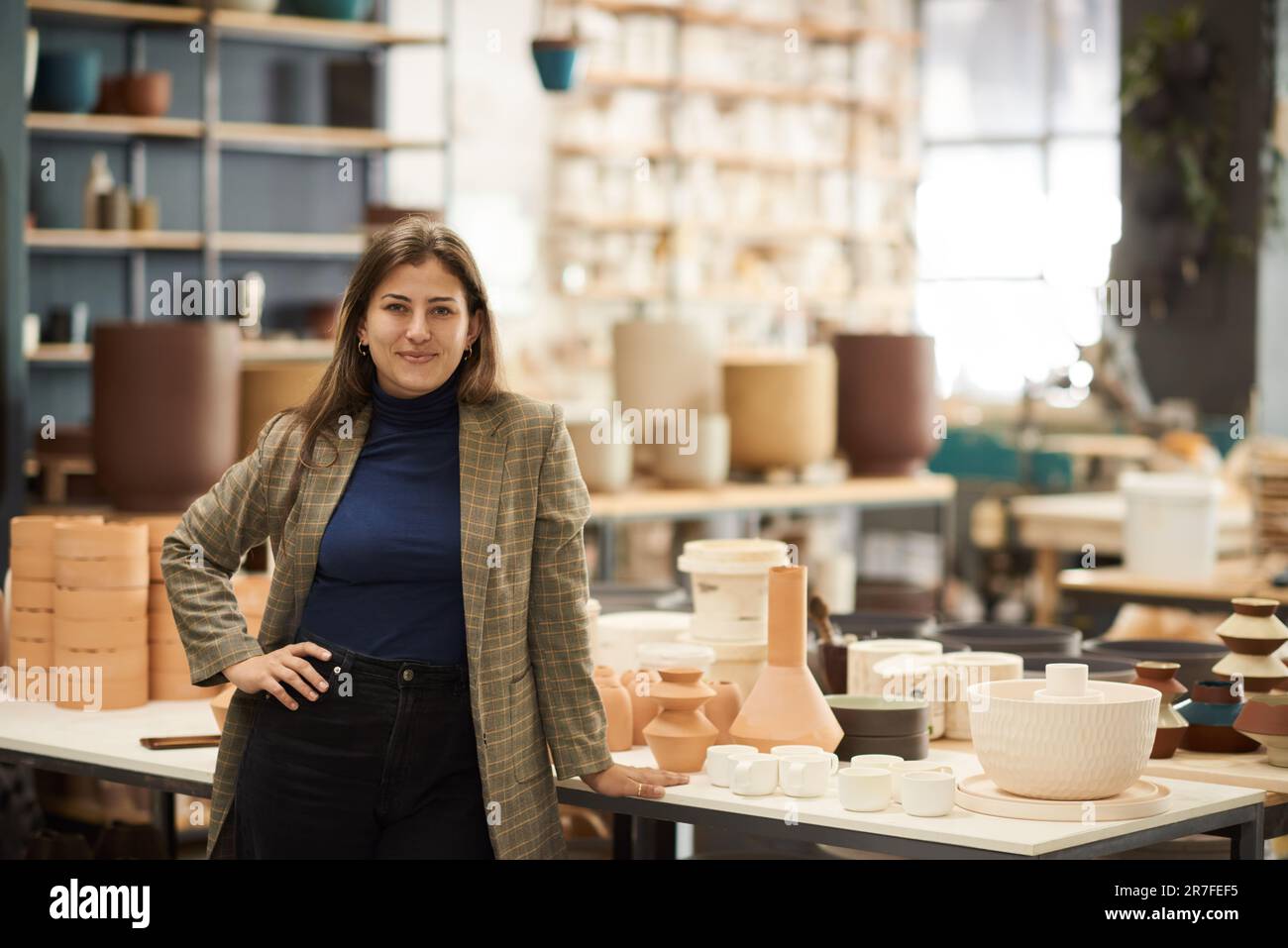 Smiling young ceramics workshop owner standing by a workbench Stock ...
