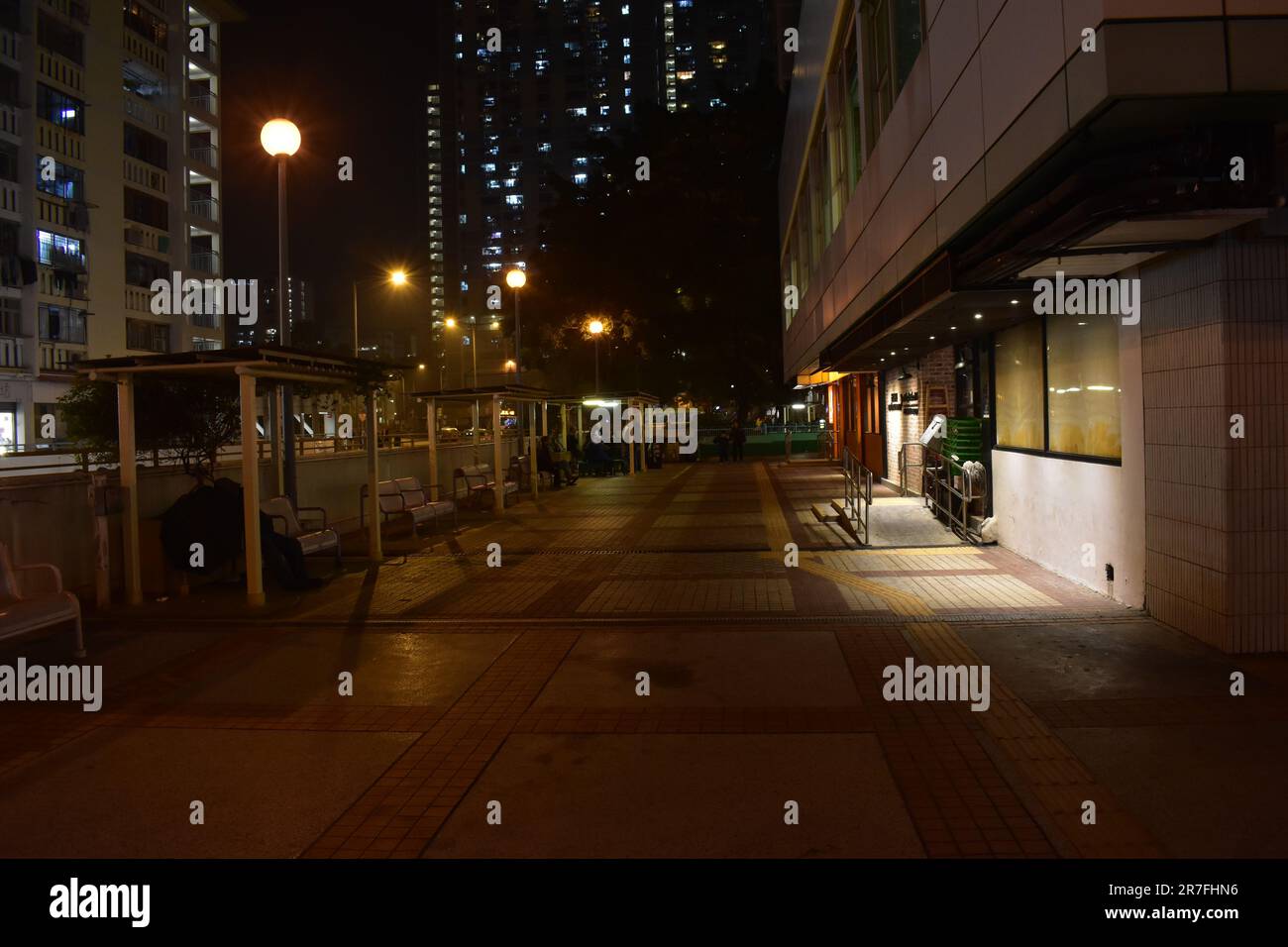 A group of people walking down a city street lit up by the evening's ...