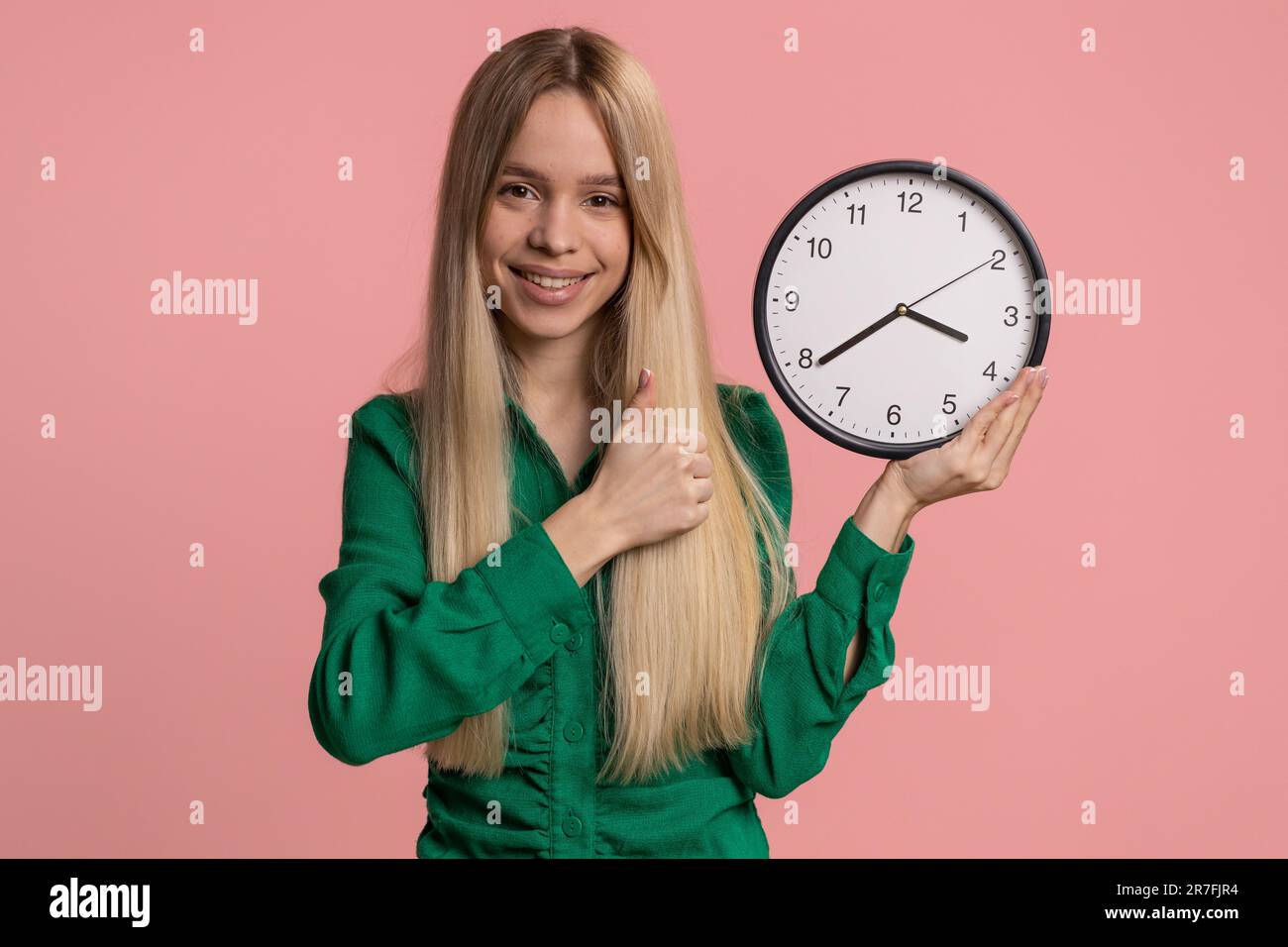 It is your time. Caucasian smiling woman showing time on wall office ...
